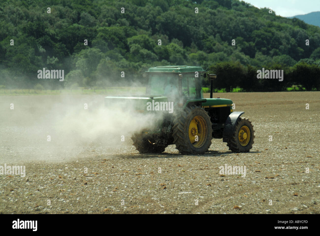 Farmer driving John Deere tractor with spreader attachment spreading ...