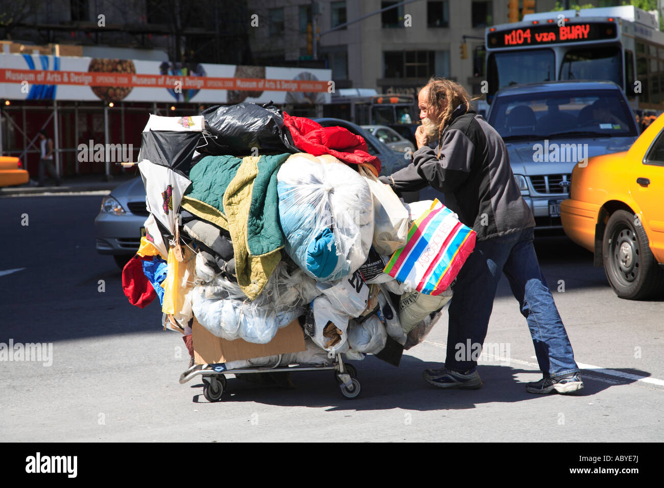 Man pushing his personal belongings in a shopping cart through traffic ...