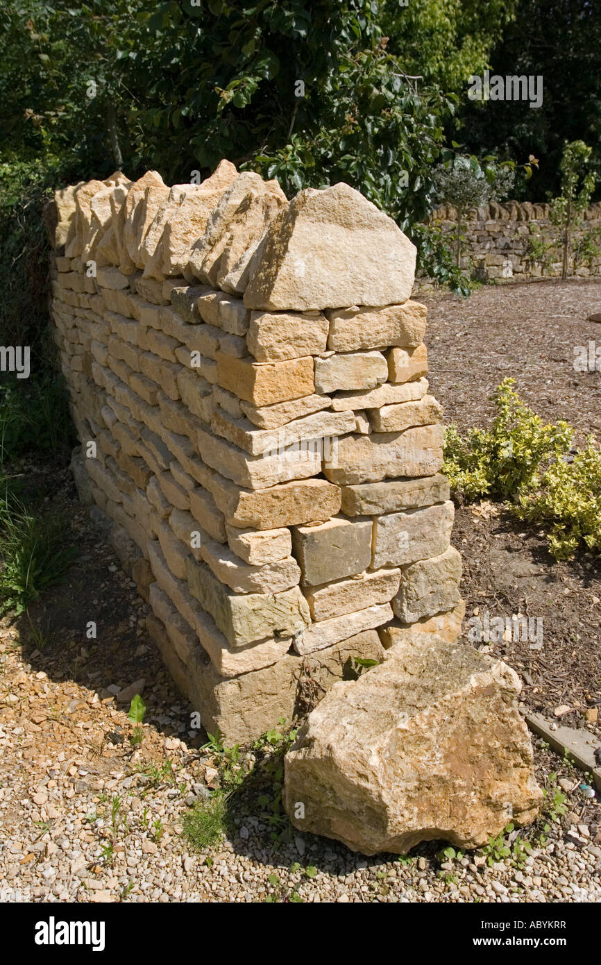 New dry stone Cotswold wall showing wide base which tapers towards top ...