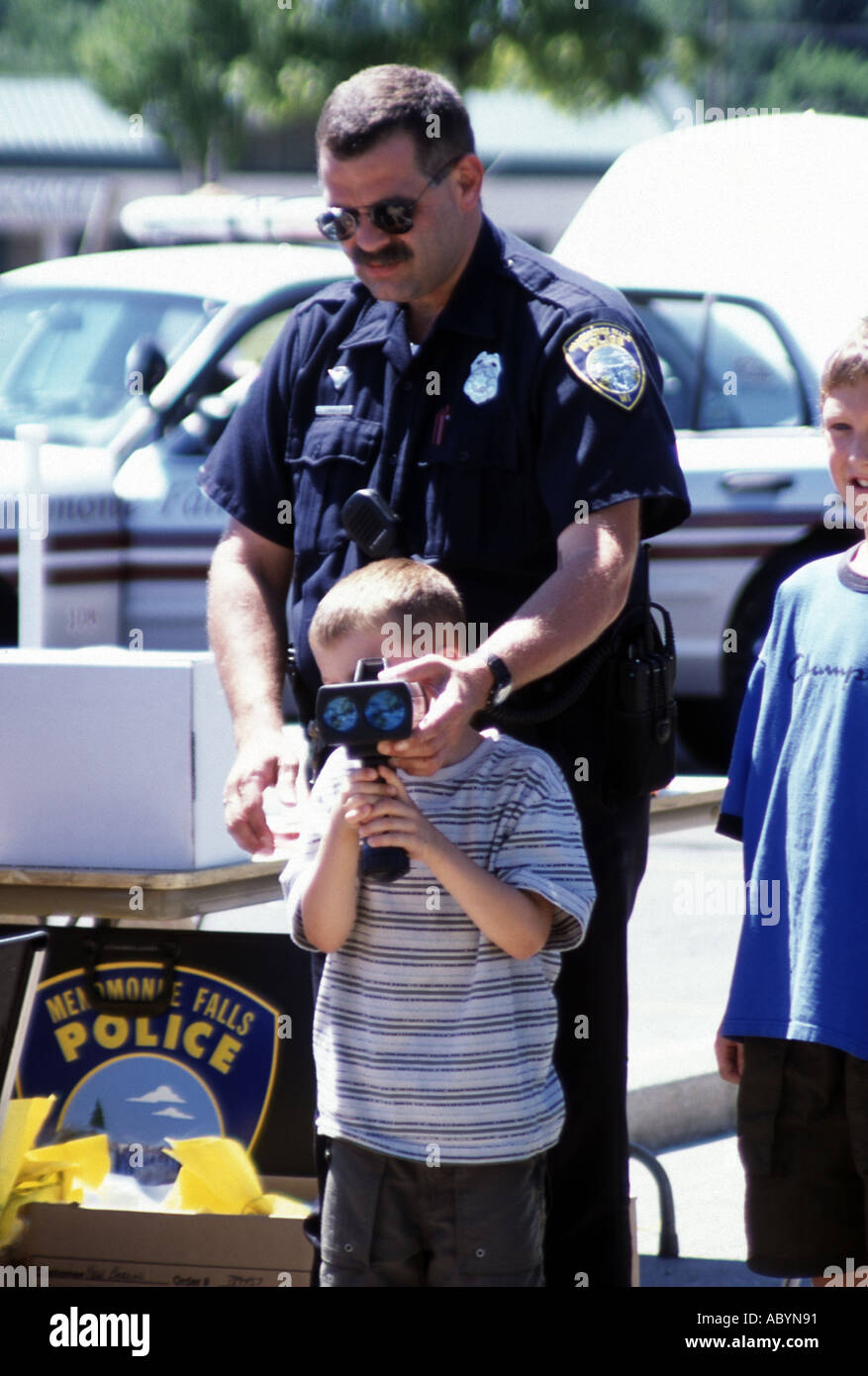 Police officer with a boy looking through a radar unit at a safety fair ...