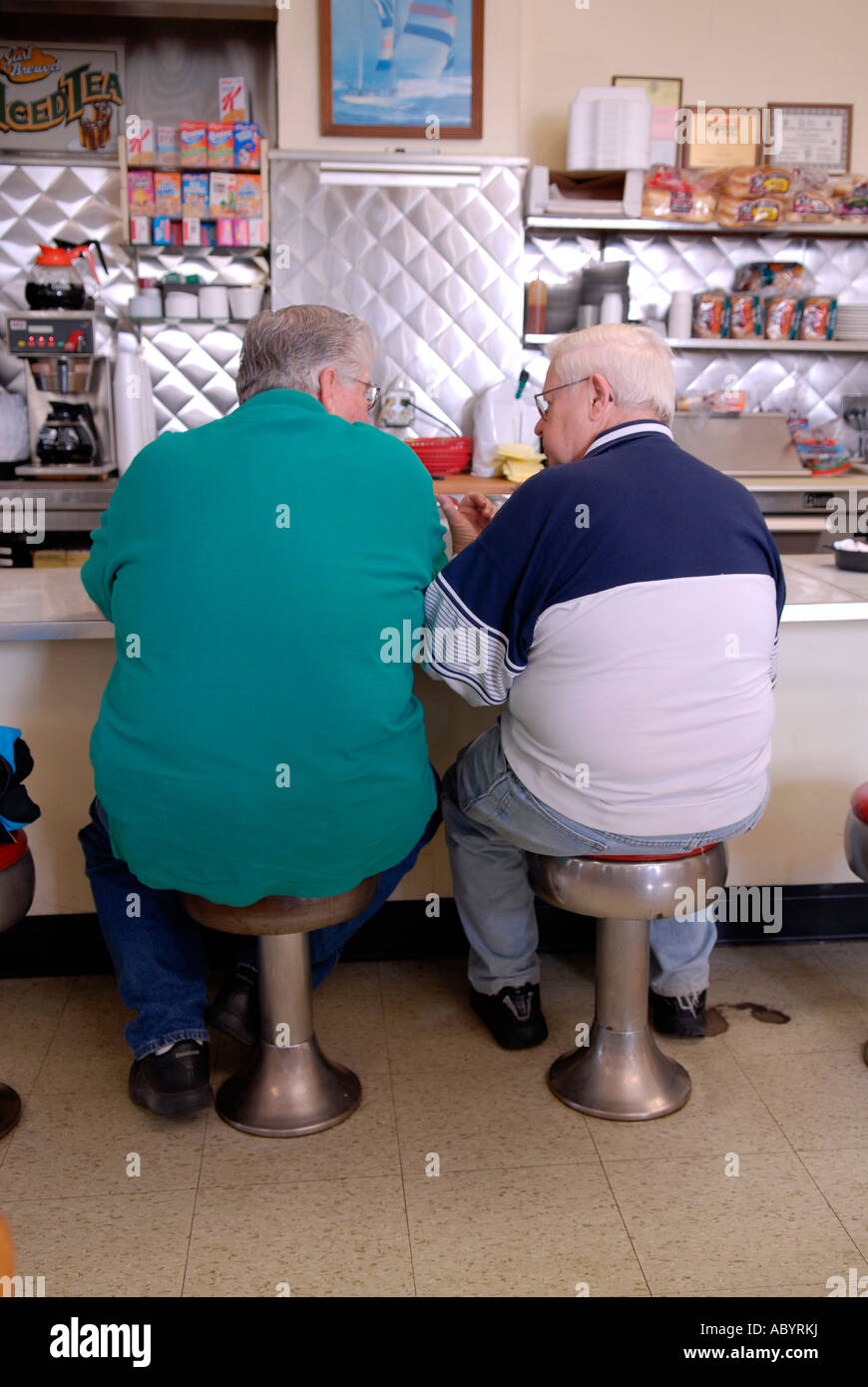 Two men sit at the counter in a small diner to eat Stock Photo - Alamy