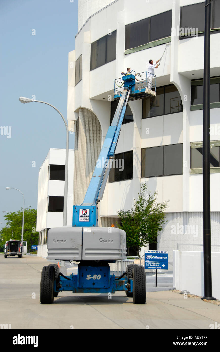 Painters on a rented portable elevator lift paint the exterior of ...
