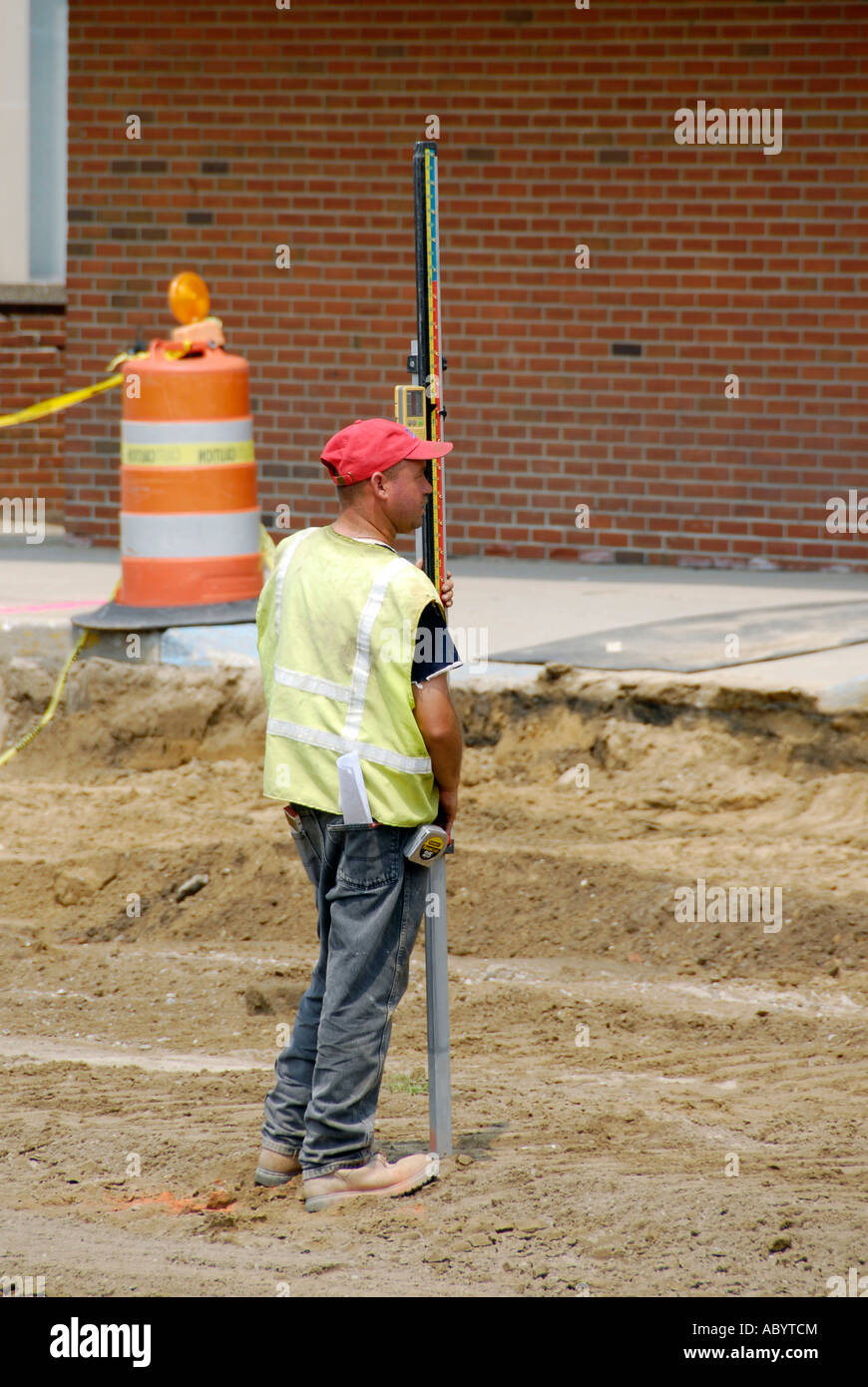 Worker with laser measuring device check for the proper depth during ...