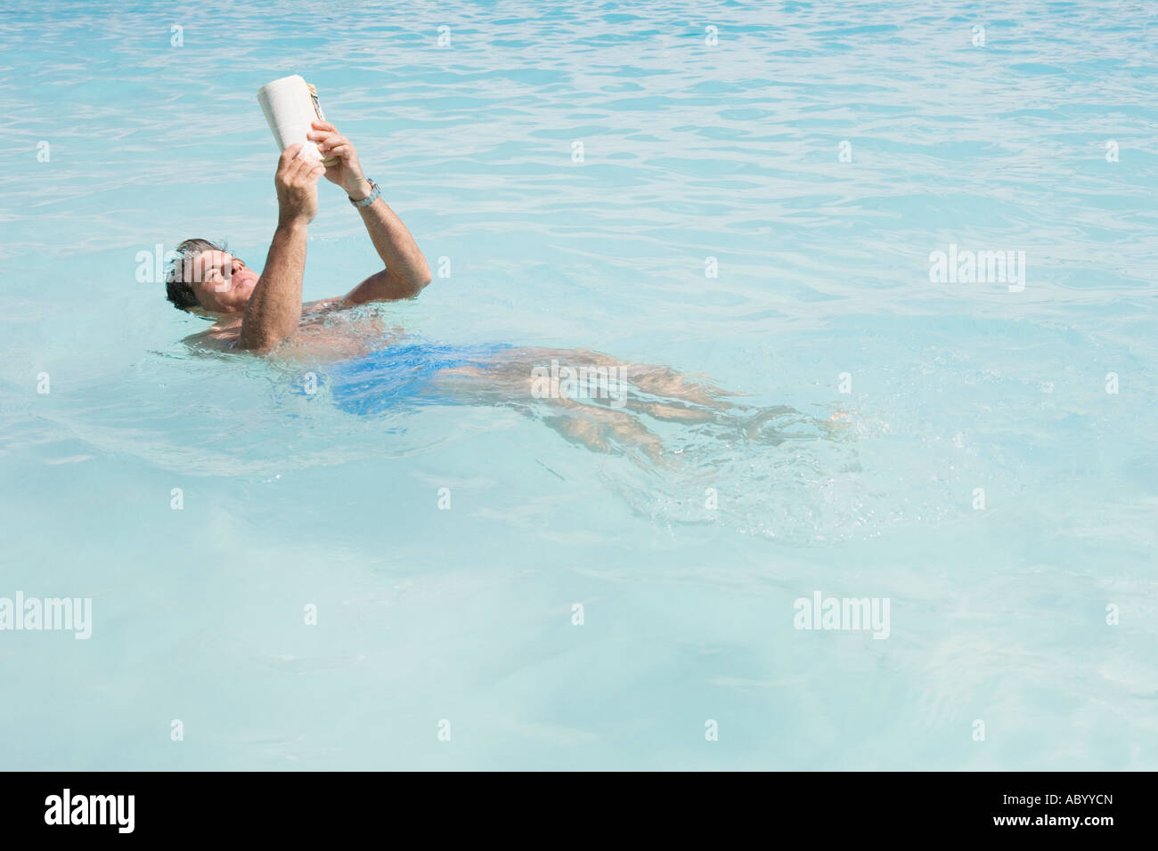 Man reading a book while floating in ocean Stock Photo - Alamy