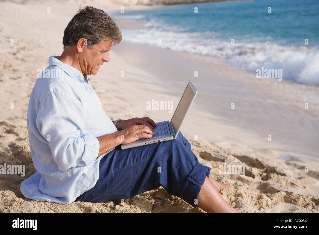 Man using laptop on beach Stock Photo - Alamy