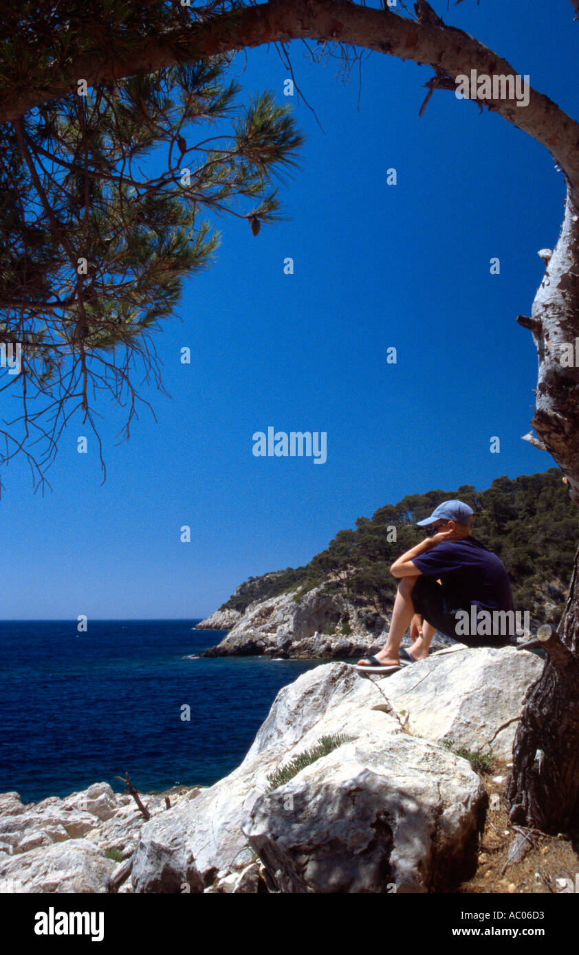 A boy looks out to sea over a beautiful Mediterranean coastline inlet ...