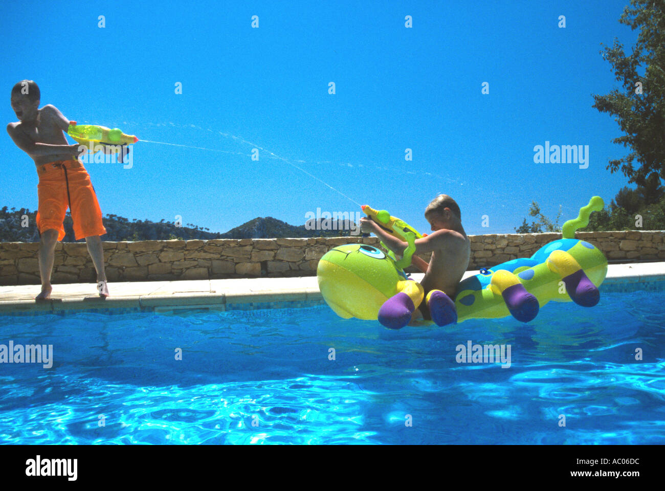 Two boys fighting with water pistols villa swimming pool Provence South ...