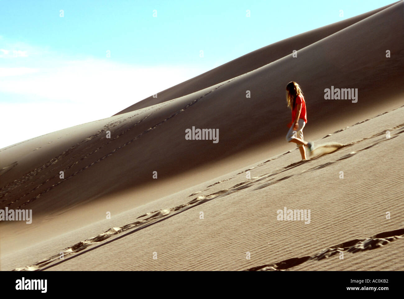 Girl walking down a sand dune in the Great Sand Dunes national Monument ...