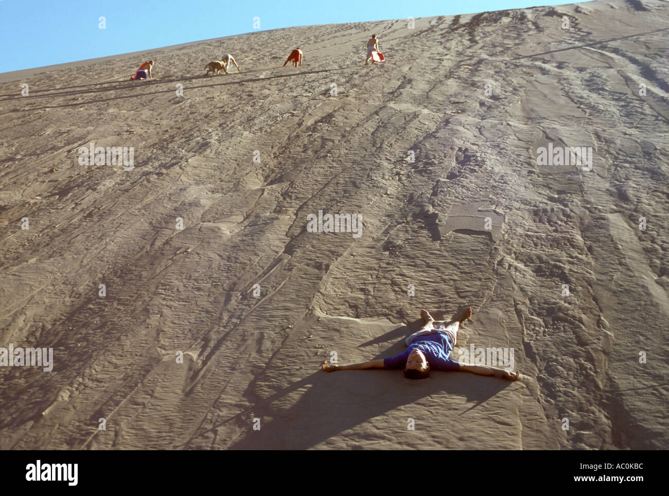 Boy falling down and playing on a sand dune at the Great Sand Dune ...