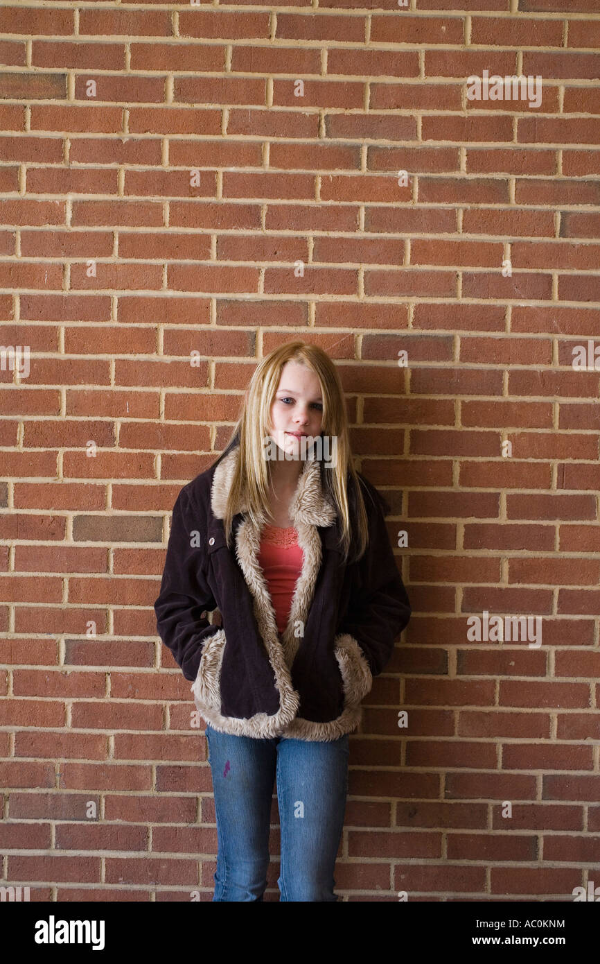 A portrait of a young girl standing against a brick wall at the mall ...