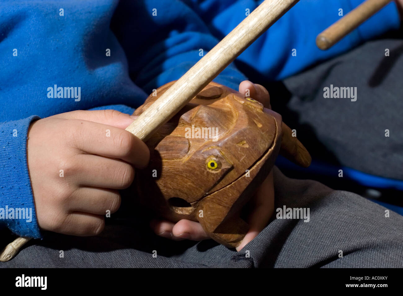 child playing a musical instrument that mimics the sound of a frog ...