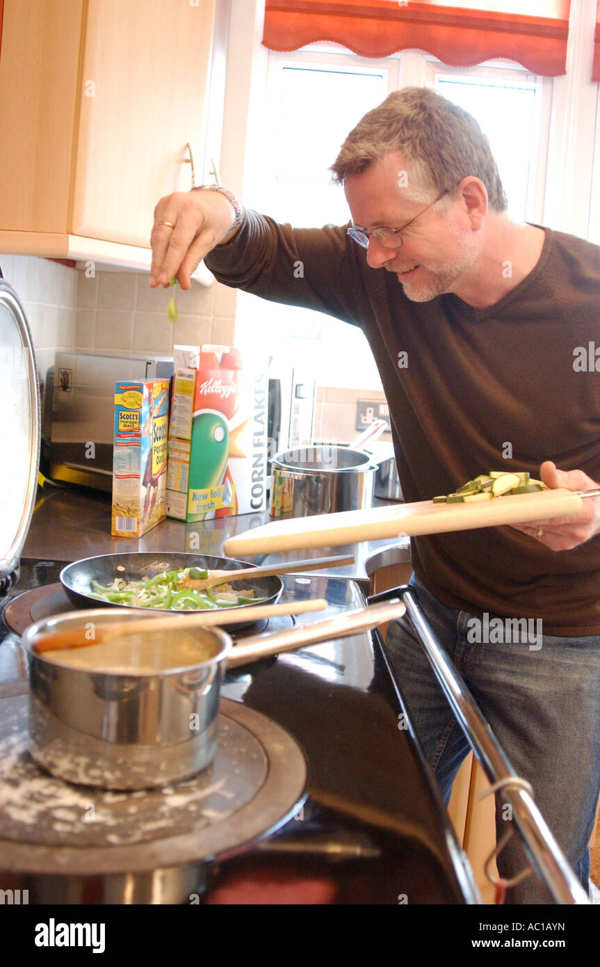 British man in kitchen cooking healthy meal for UK family London ...