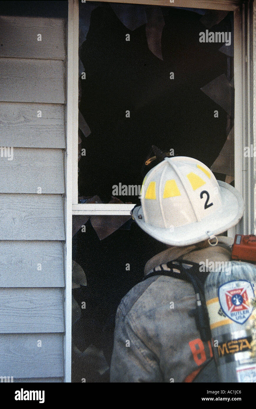 Fire fighter looking into broken window of a burnt room that was on ...
