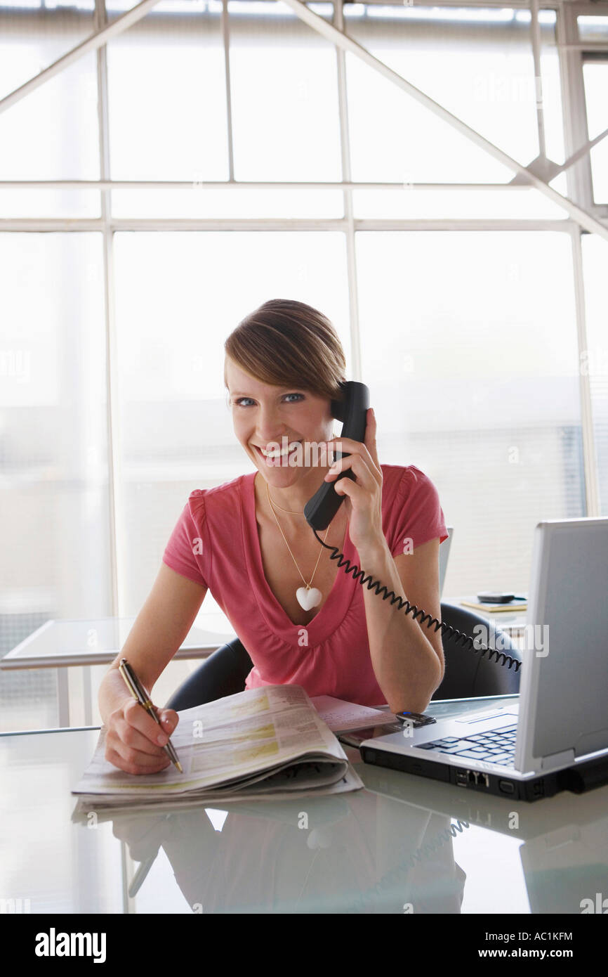 Woman at desk using phone Stock Photo - Alamy