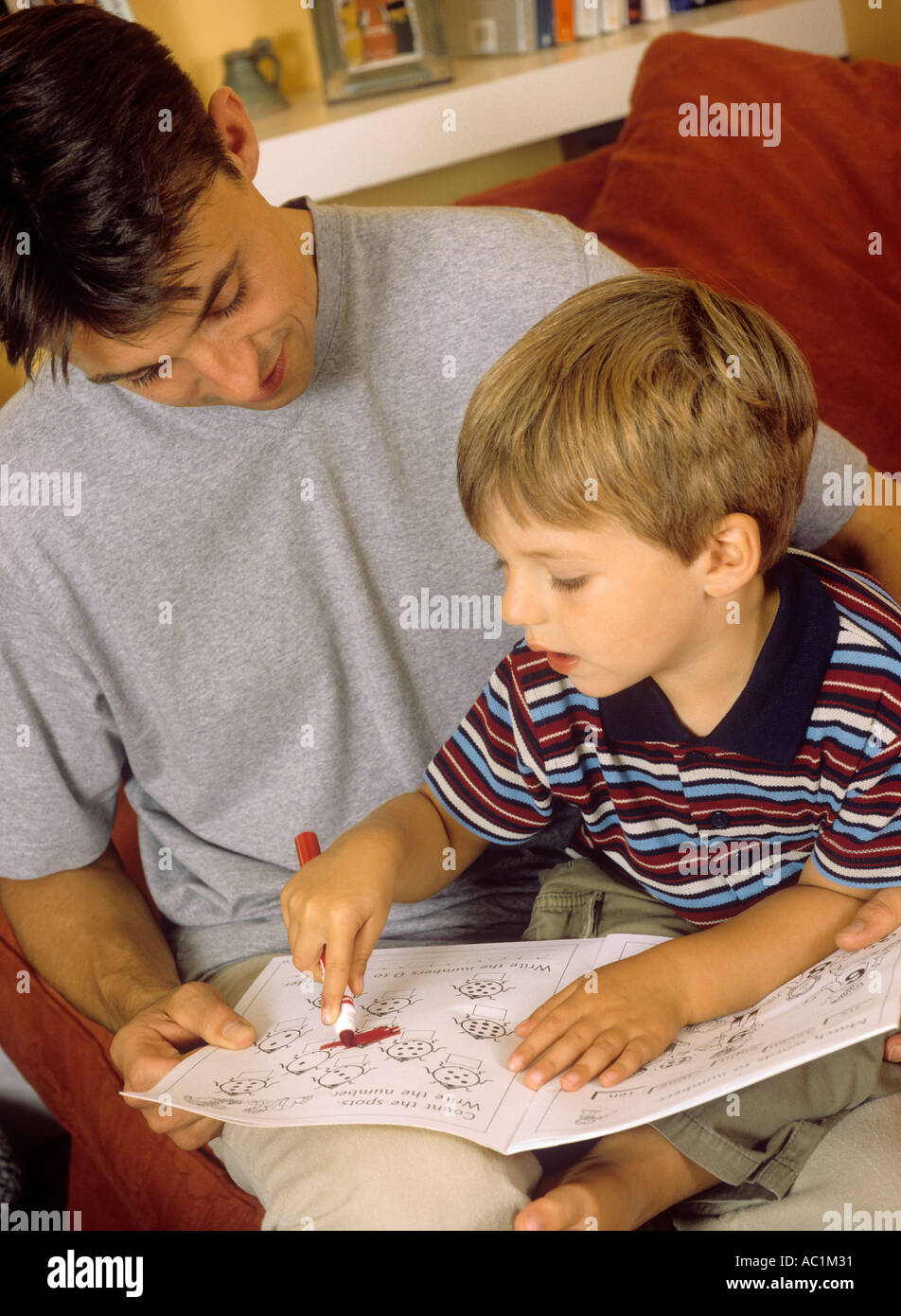 Father watching his young son play with a colouring book Stock Photo ...