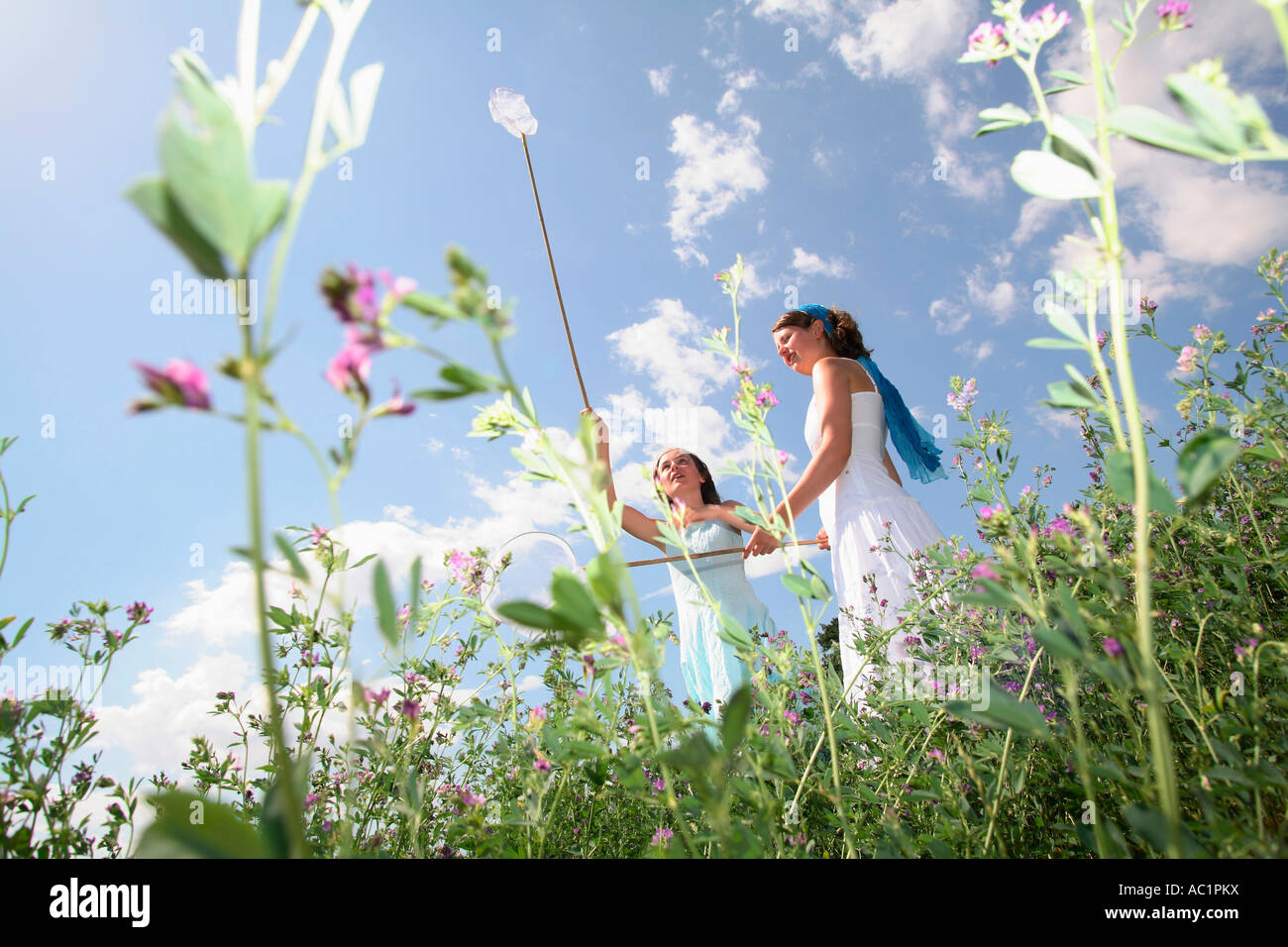 Two young women catching butterflies Stock Photo - Alamy