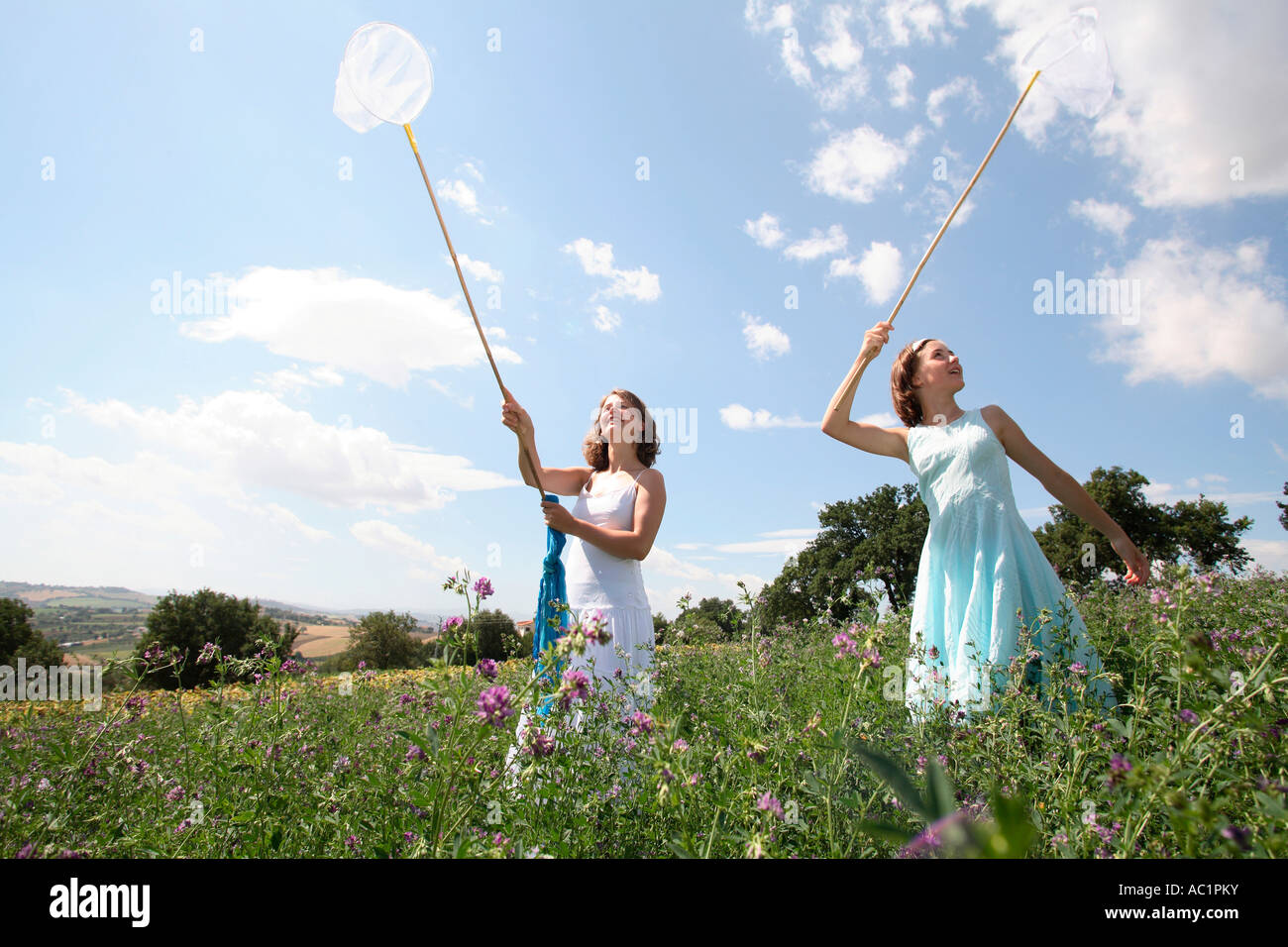 Two young women catching butterflies Stock Photo - Alamy