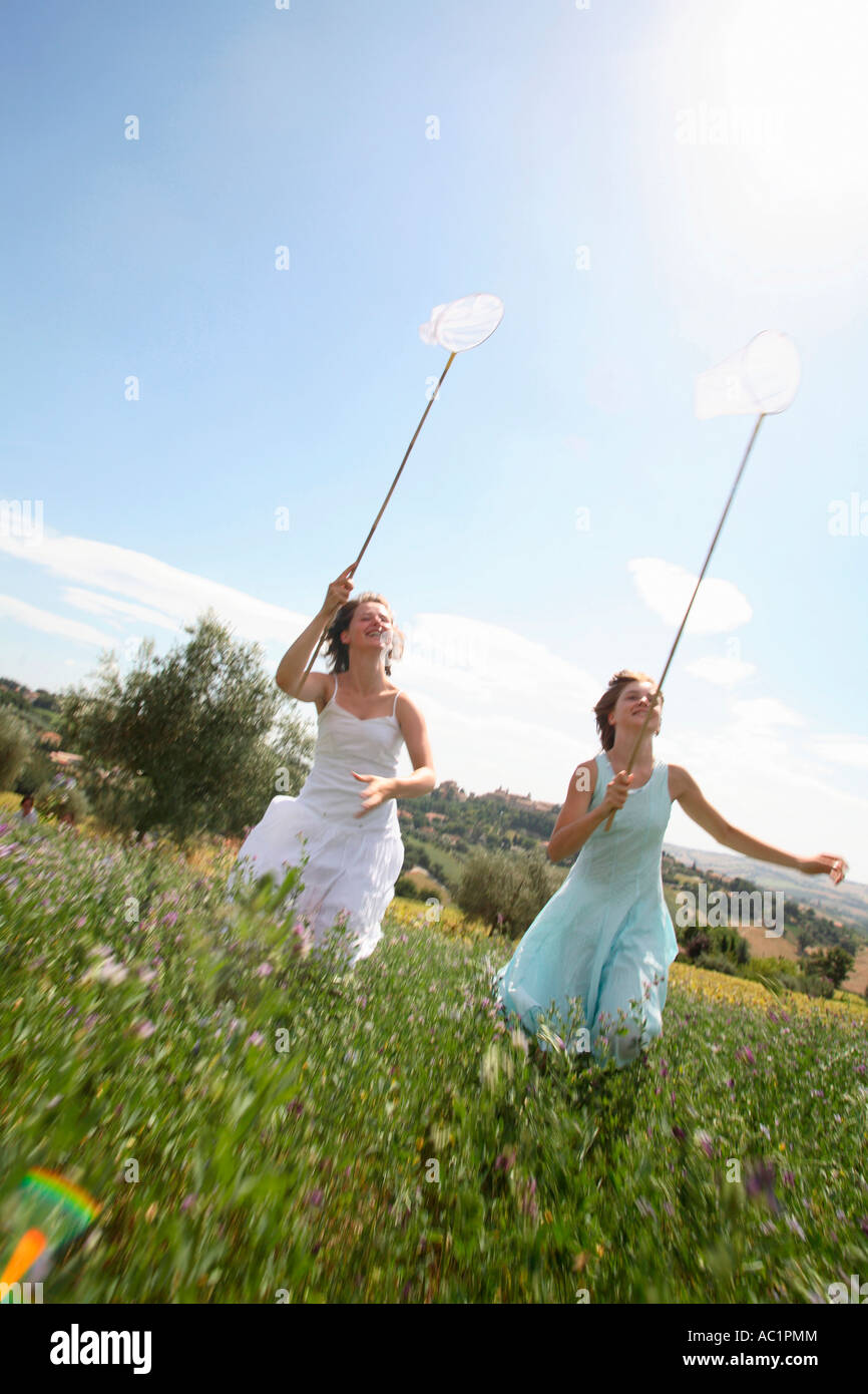 Two young women catching butterflies Stock Photo - Alamy