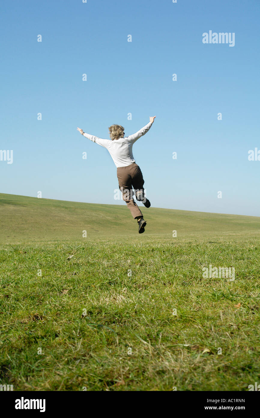 Woman jumping in meadow, rear view Stock Photo - Alamy