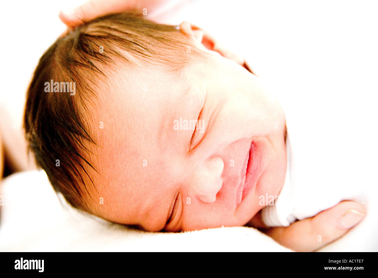 Newborn baby lying down pulling face Stock Photo - Alamy