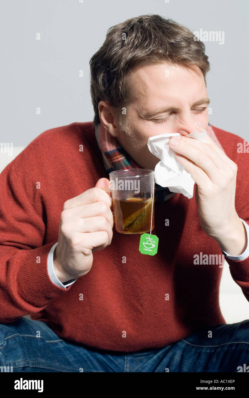 Man having a cold teacup in hand blowing his nose Stock Photo - Alamy