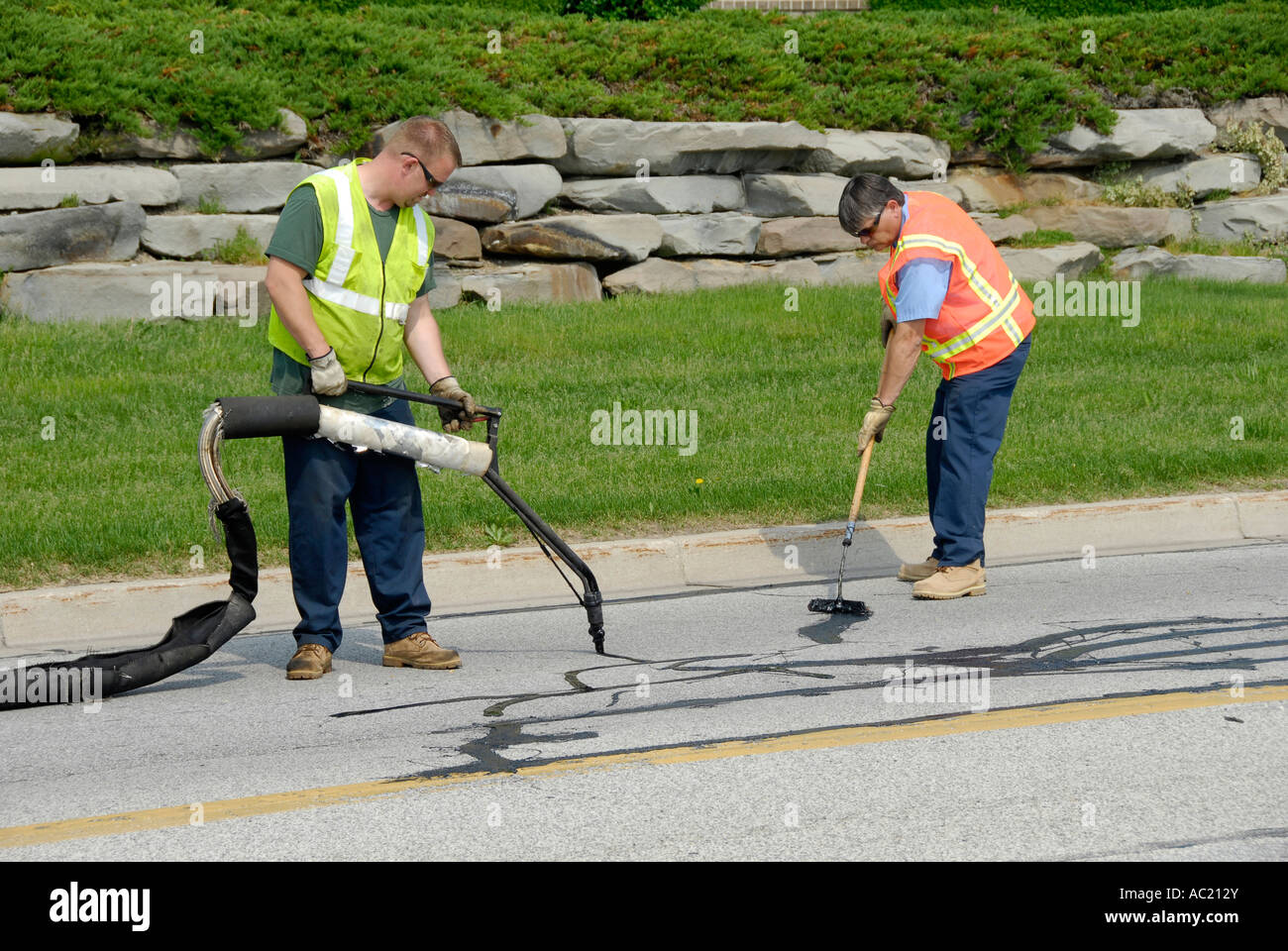 Road workers pour tar in the cracks of street pavement Stock Photo - Alamy