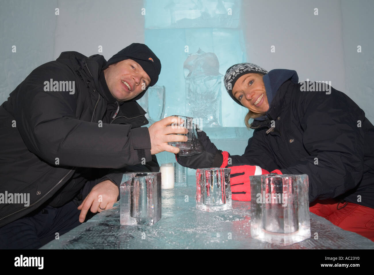 A woman and a man clinking glasses made of ice in the icebar of the ...