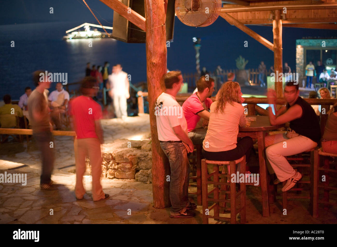 Tourists sitting in the open air club of Cavo Paradiso Paradise Beach ...