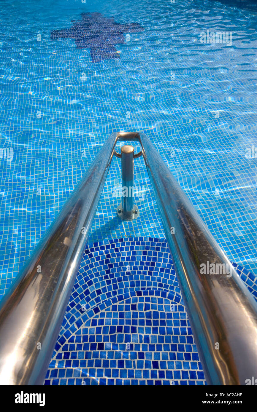 Abstract of railings by pool steps leading down into blue swimming pool ...