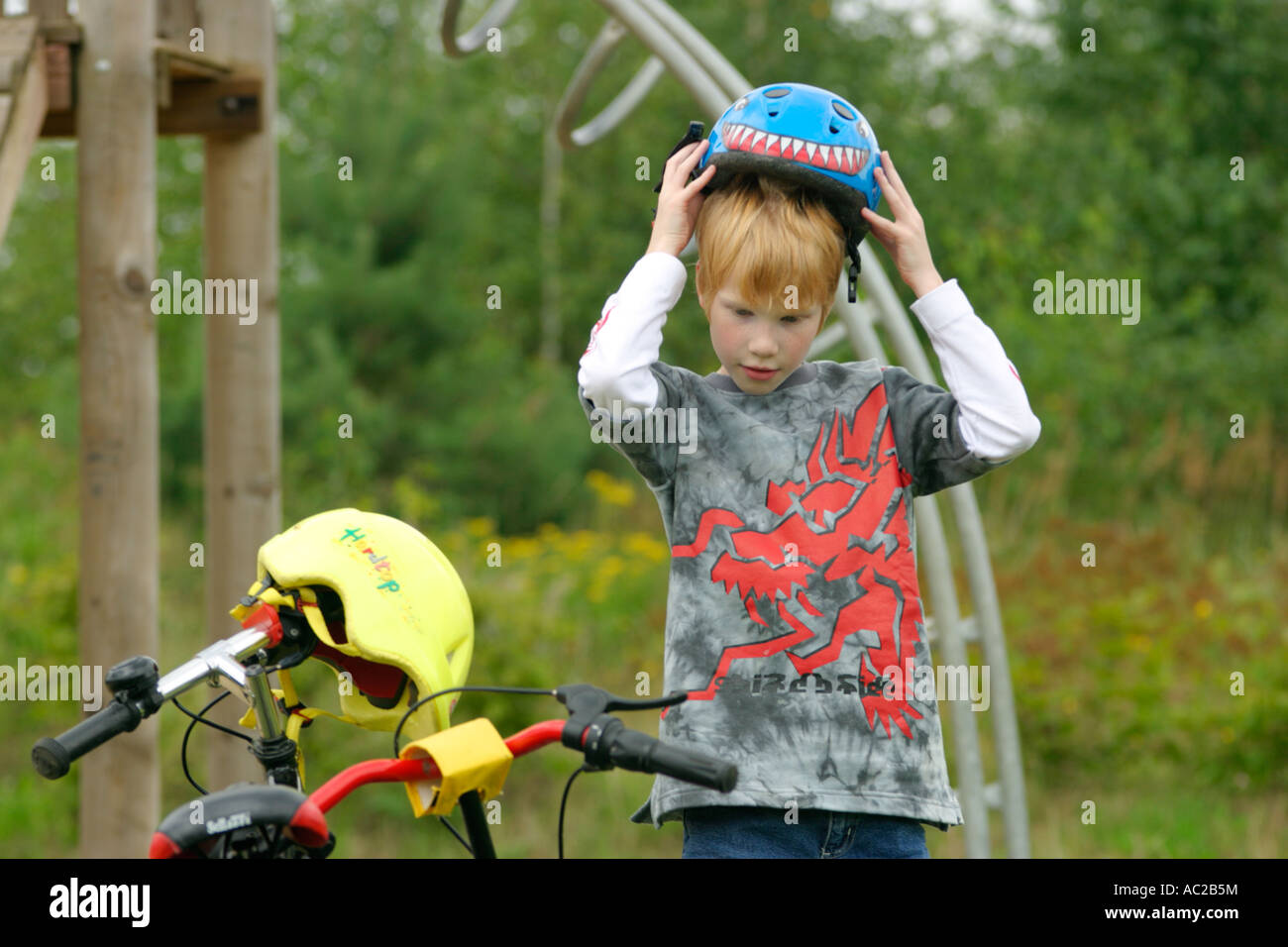 a young boy taking off his bicycle helmet before playing on a ...