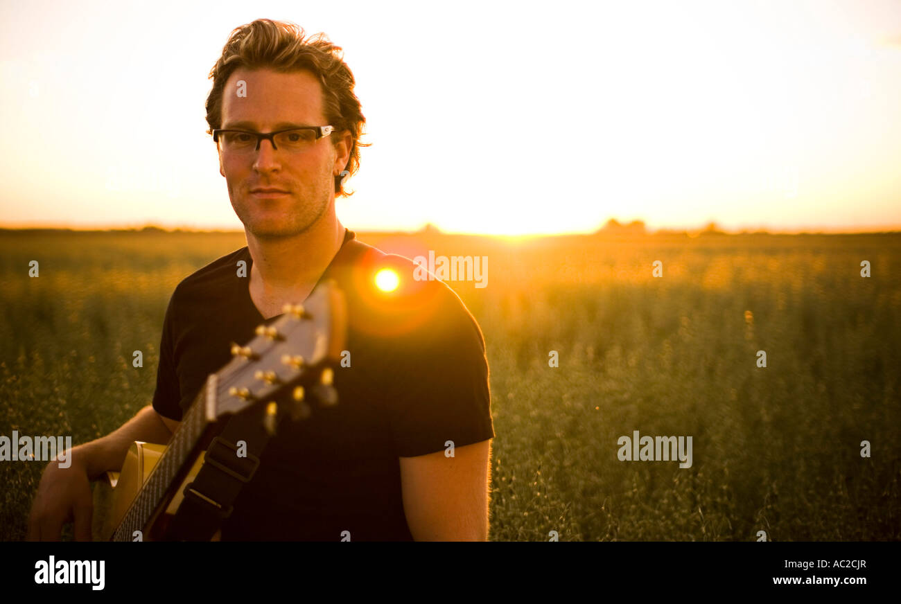 Musician Marcus Eaton at sunset in a field with gutar Stock Photo - Alamy