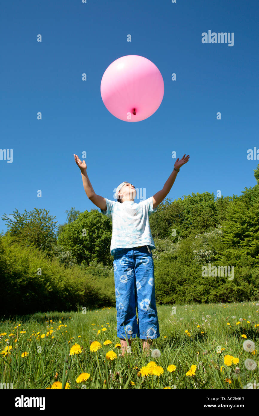 young girl trying to catch a big pink balloon Stock Photo - Alamy