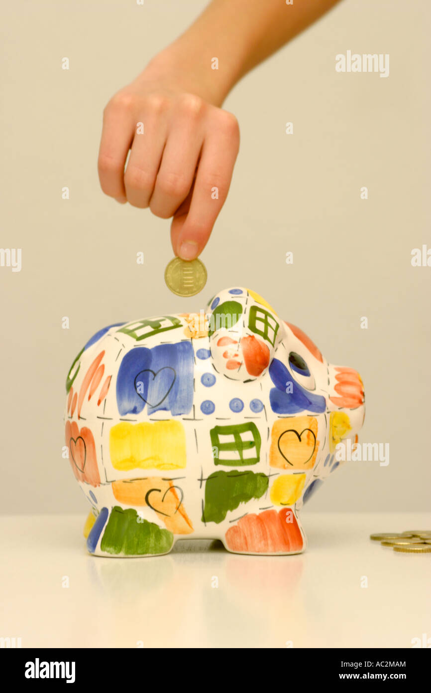 a coin being put into a piggy bank Stock Photo - Alamy