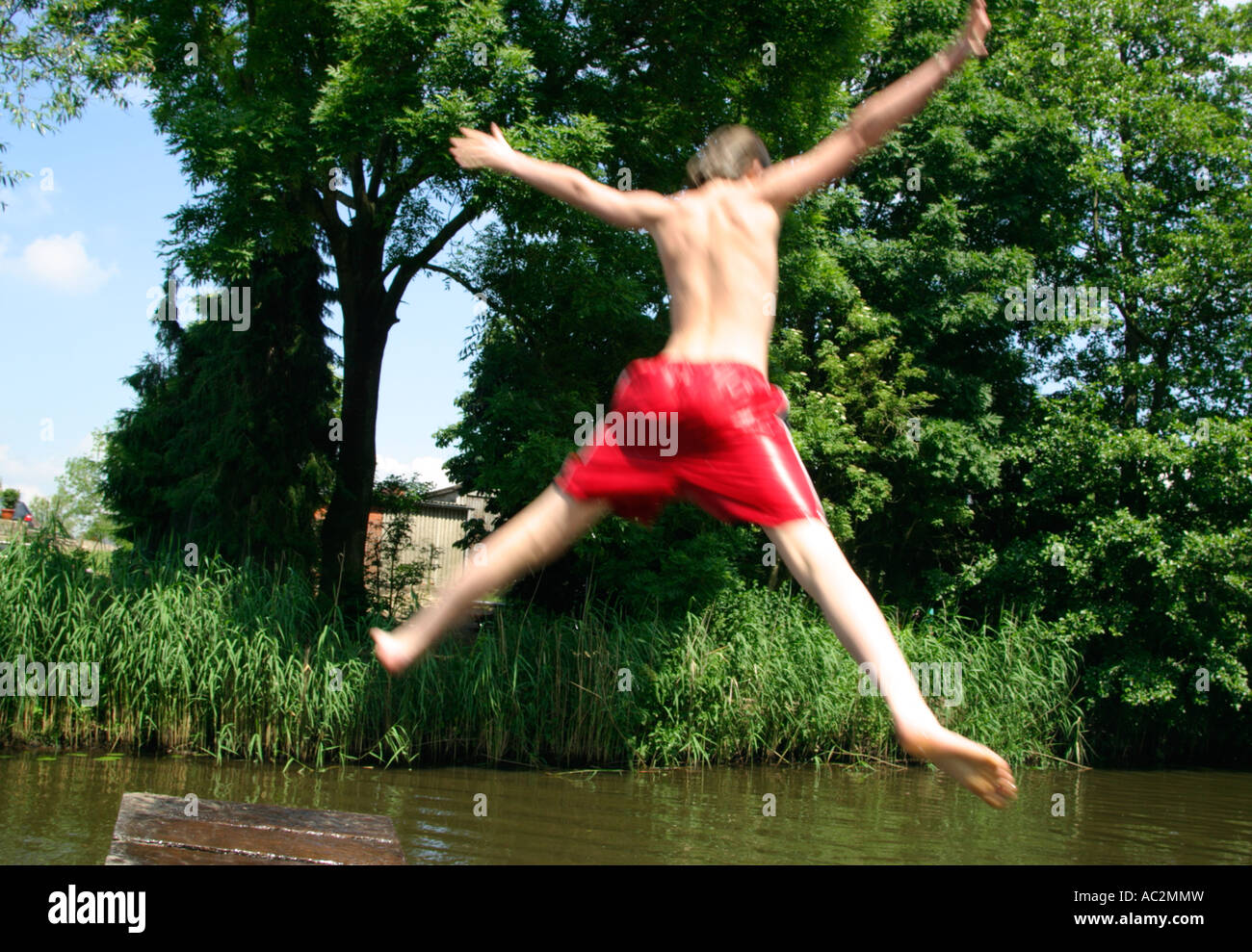 a young boy is jauntily jumping into a river Stock Photo - Alamy