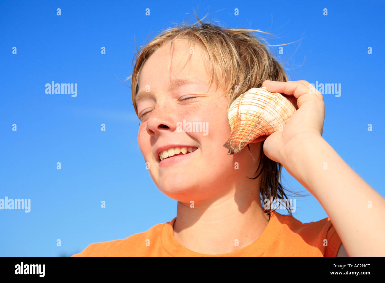 portrait of a young boy listening to a shell Stock Photo - Alamy