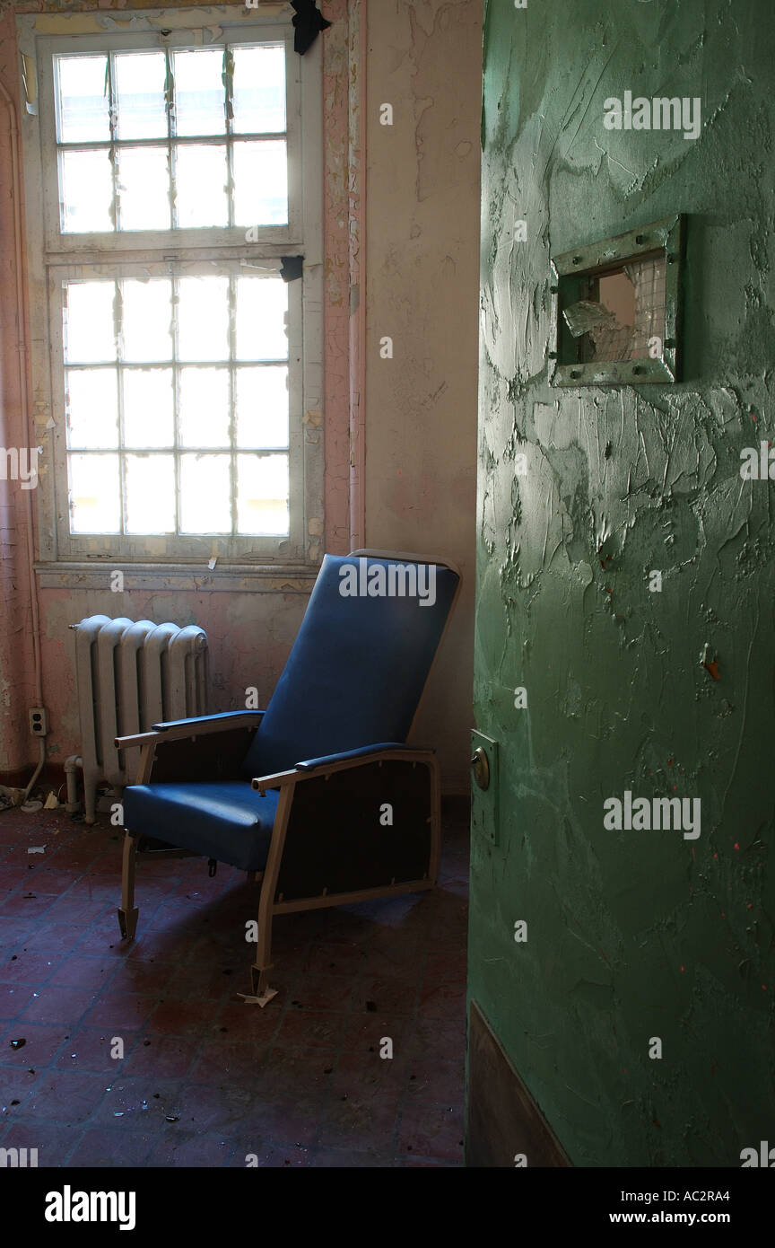 Broken blue chair with window and green door in abandoned psychiatric ...