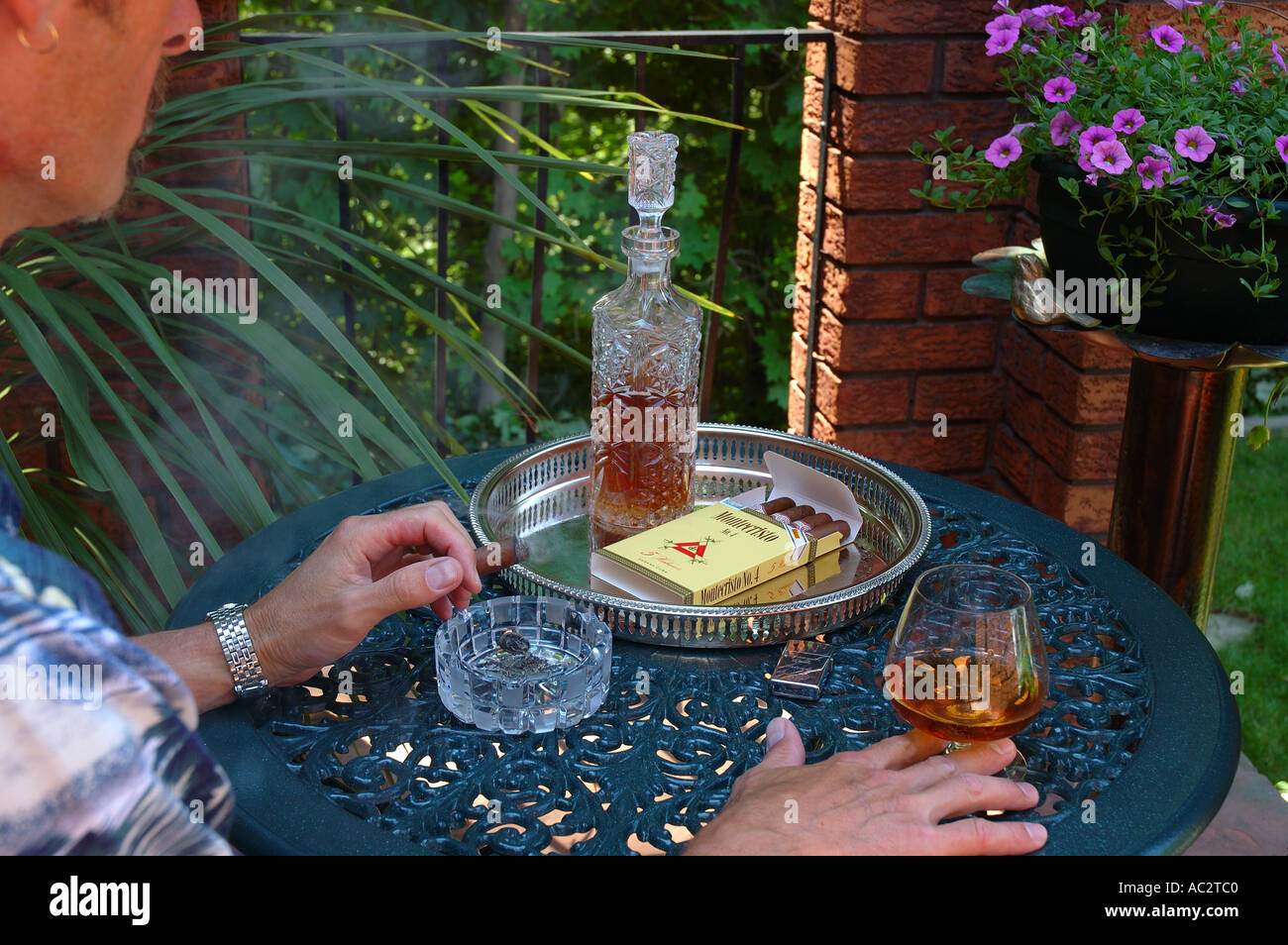 Man smoking cuban cigars and drinking cognac in summer at an outdoor ...