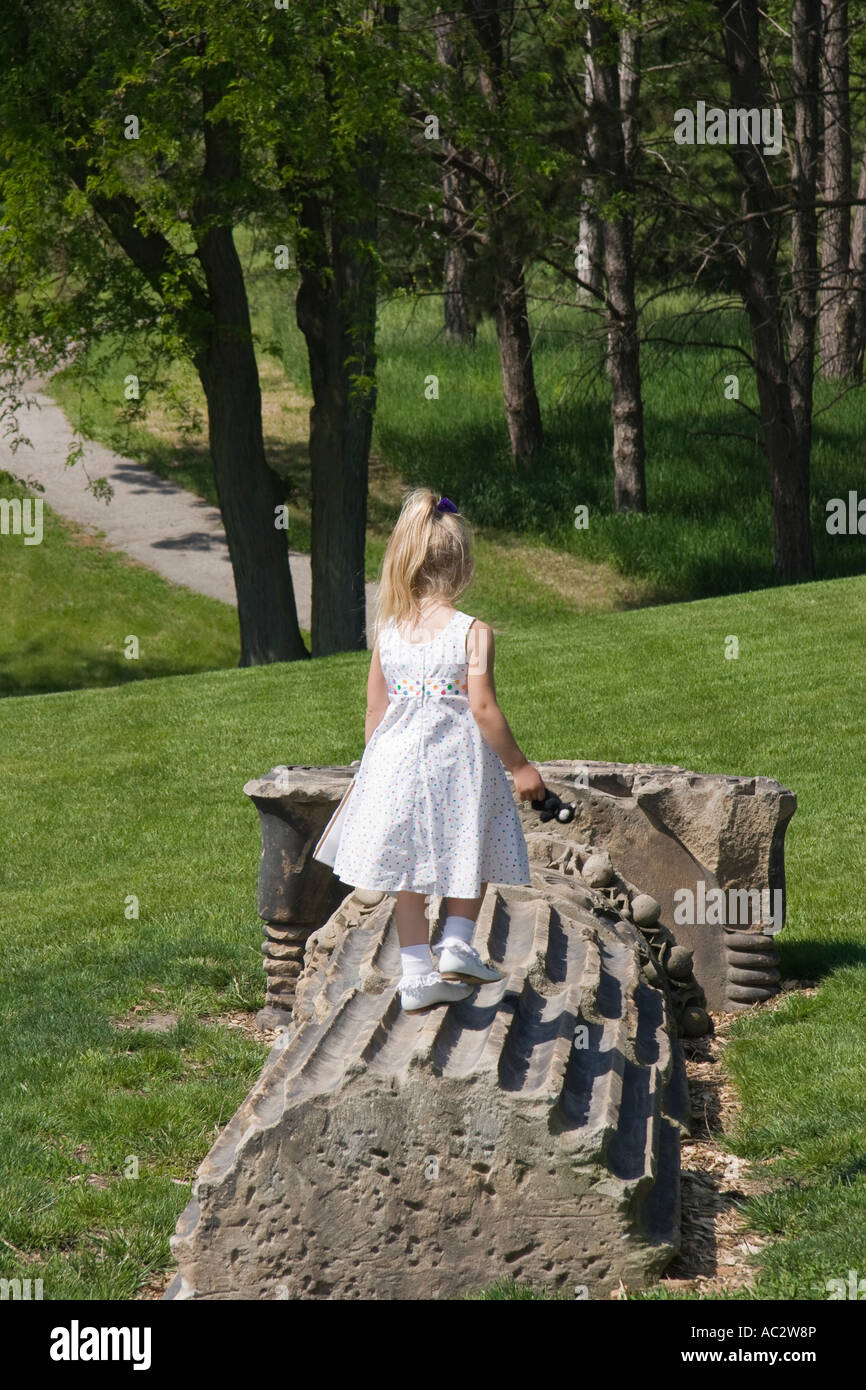 Young girl walking on Roman column in green park setting Stock Photo ...