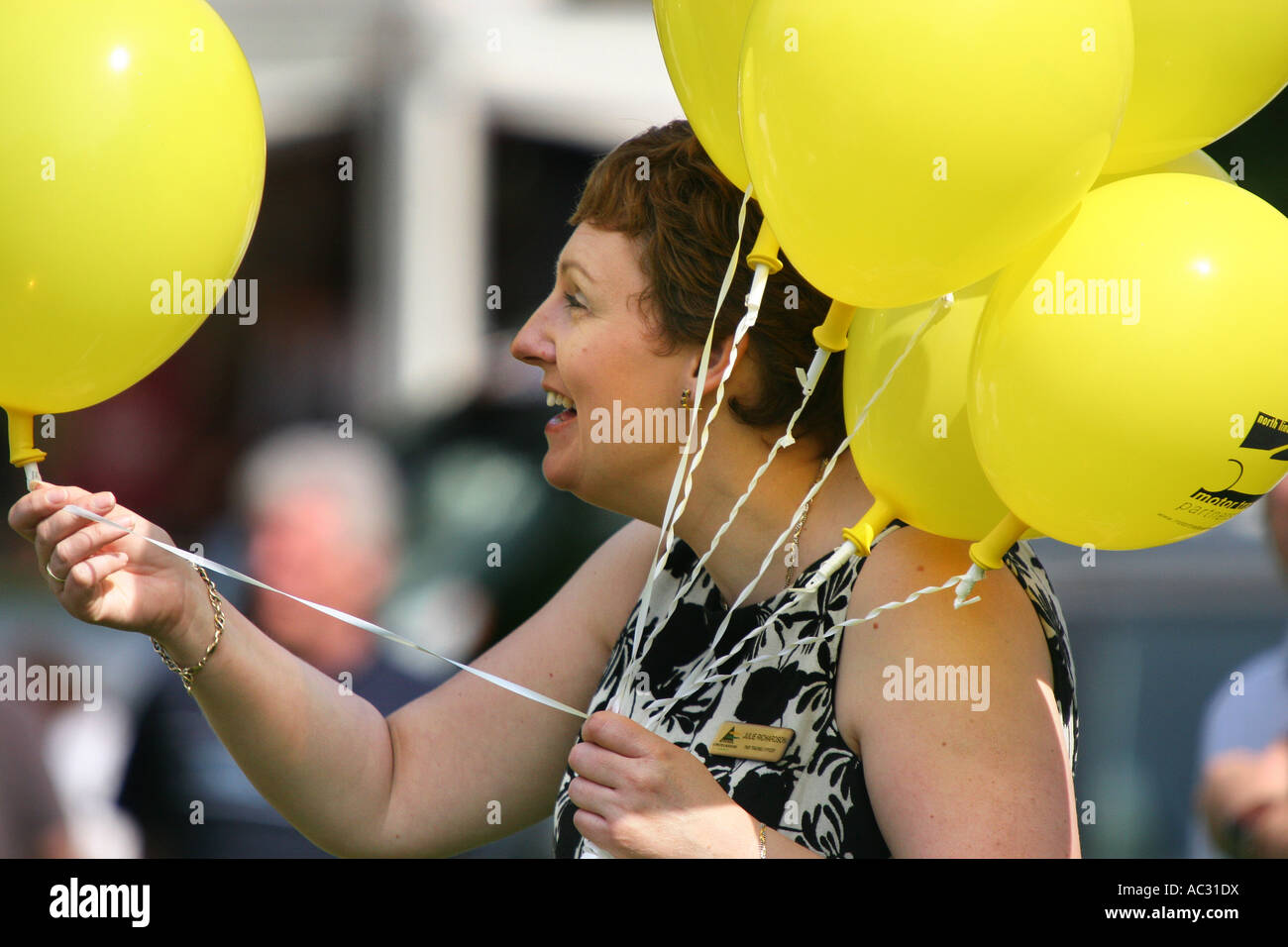 Lady giving yellow balloons to children at an advertising event Stock ...