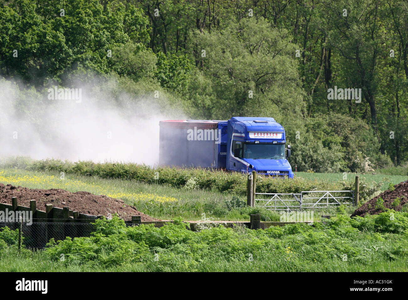 Dust cloud behind large articulated lorry on small farm track Stock ...