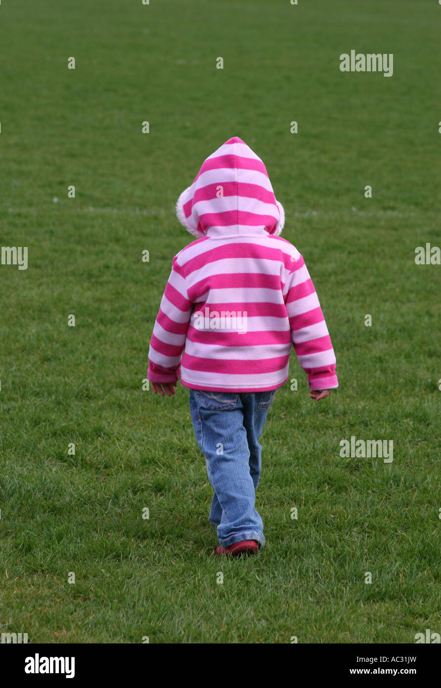 Small girl walking away from the camera in a hooded red stripped top ...