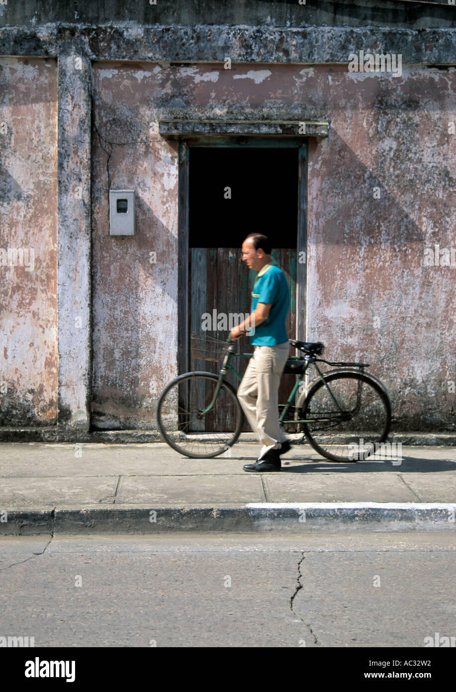 cuban walking with bicycle against derelict street side building Stock ...