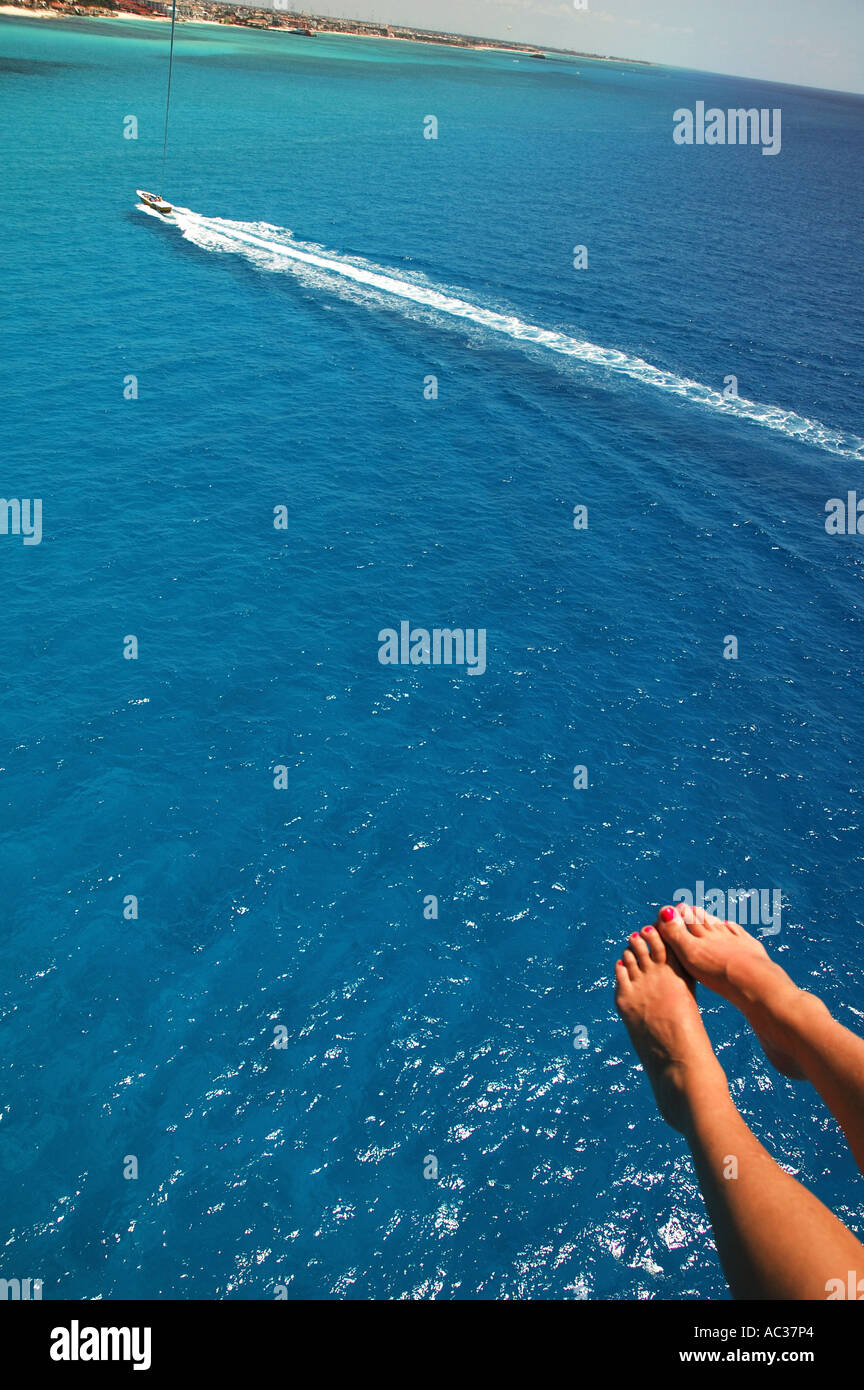 A pair of feet are in the foreground as a boat tows a parasail as the ...