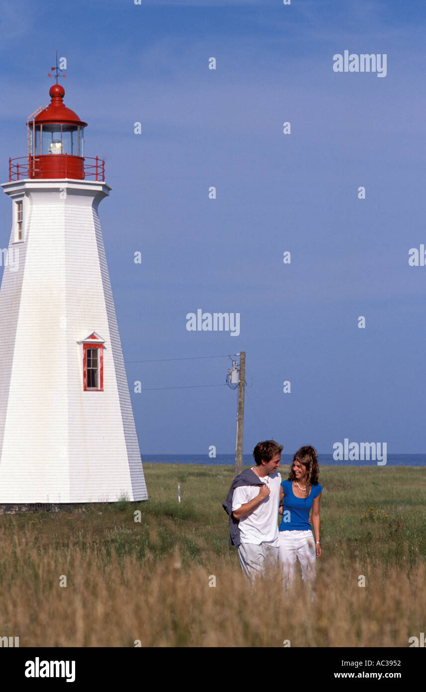 young caucasion couple walking by lighthouse in New Brunswick Canada ...
