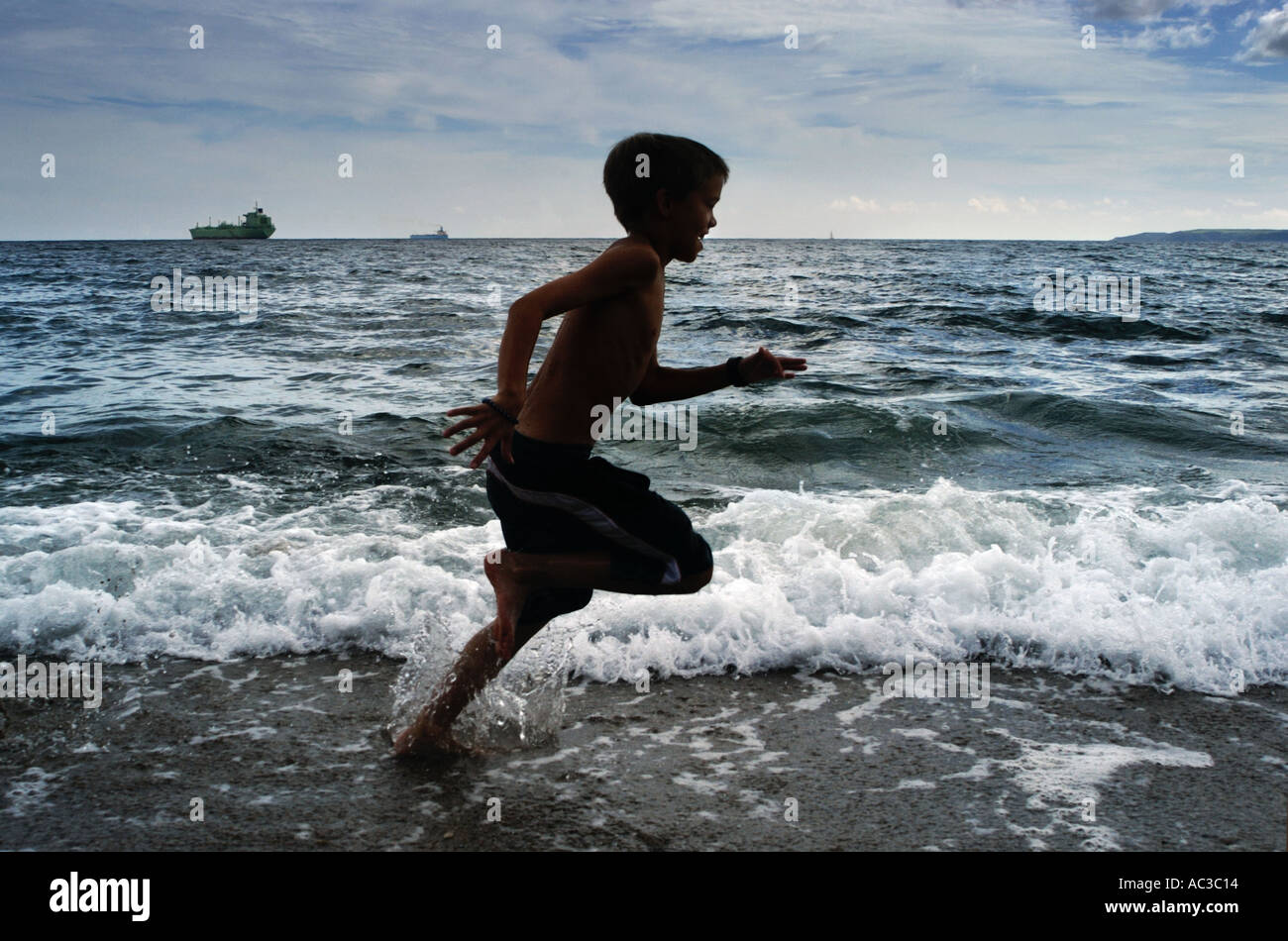 Boy running along the shoreline Stock Photo - Alamy
