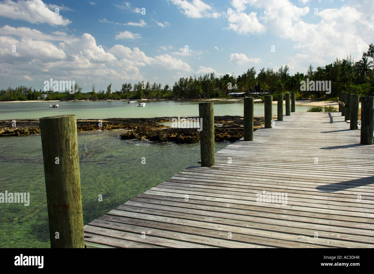 Wooden walkway over tropical sea with boats blue sky and clouds Stock ...