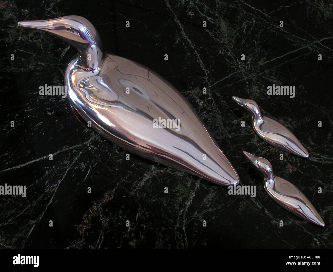 Silver Ducks swimming on black marble Stock Photo - Alamy