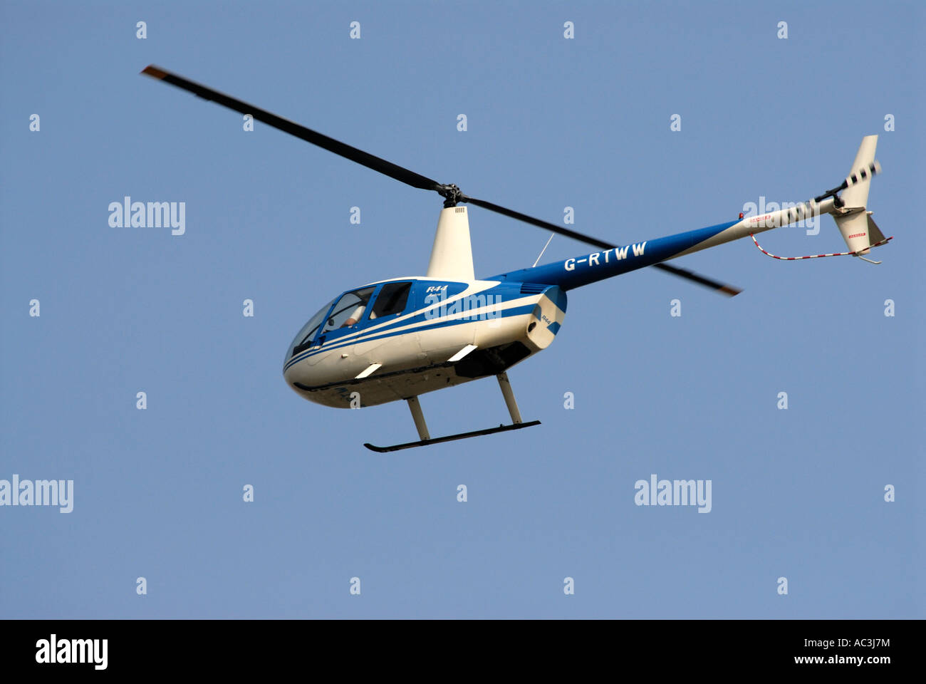 Robinson R44 helicopter in flight against blue sky Stock Photo - Alamy