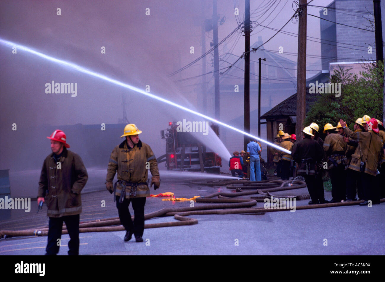 Firefighters / Firemen fighting a Fire with Hose and Water Stock Photo ...