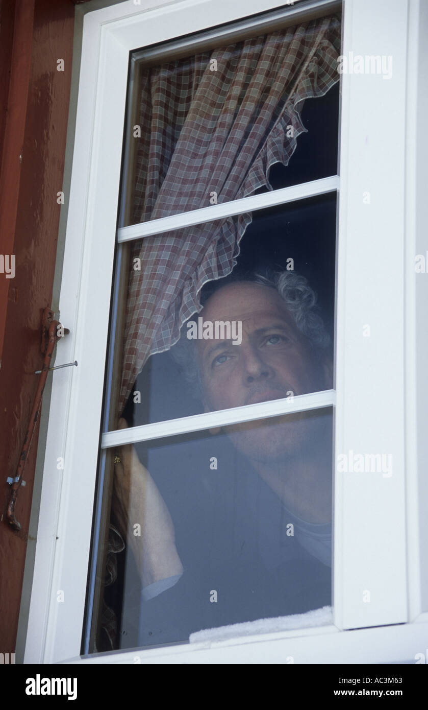 Male person looking through the window of a mountainhut in Switzerland ...
